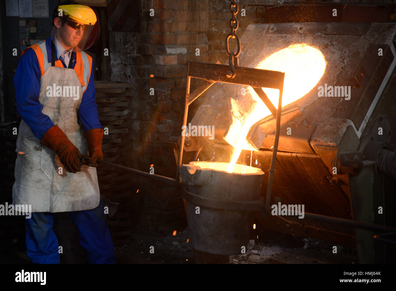 Foundrymen pour molten iron from an induction furnace into the ladel at ...