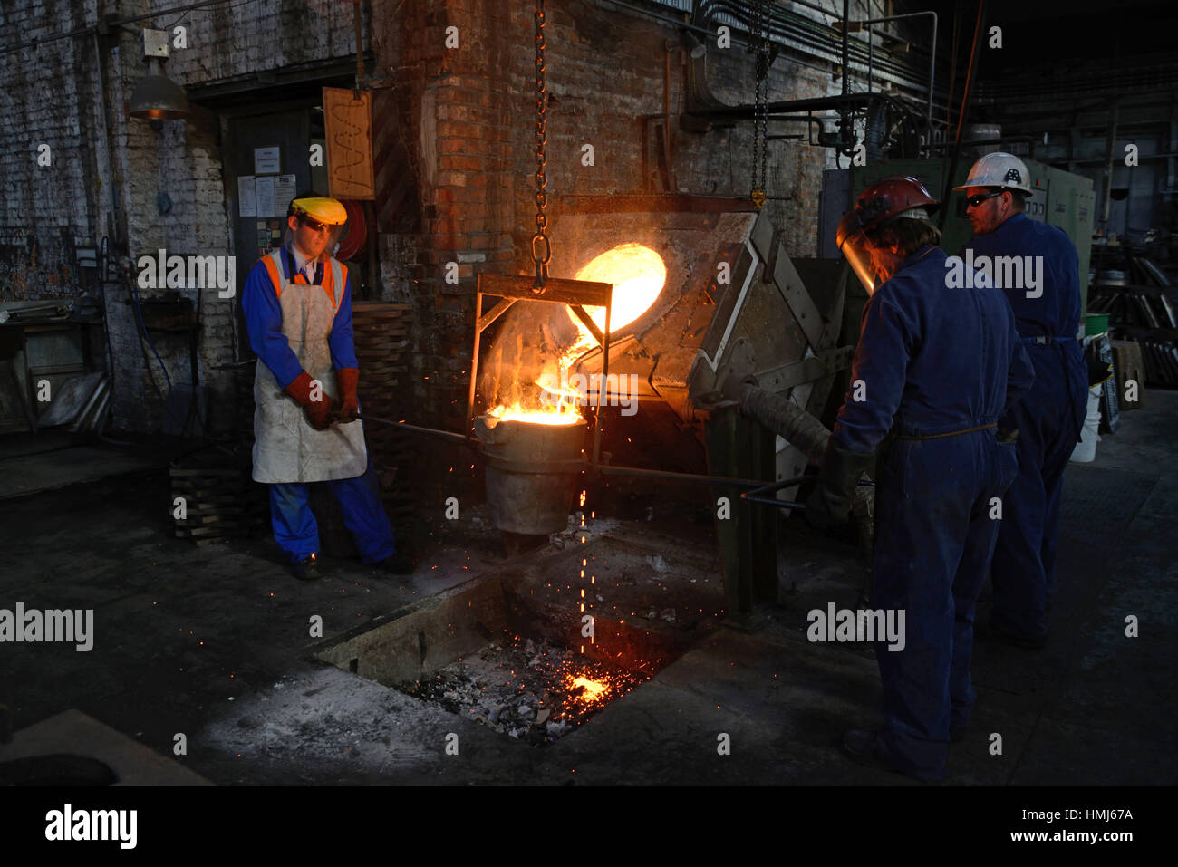 Foundrymen pour molten iron from an induction furnace into the ladel at ...