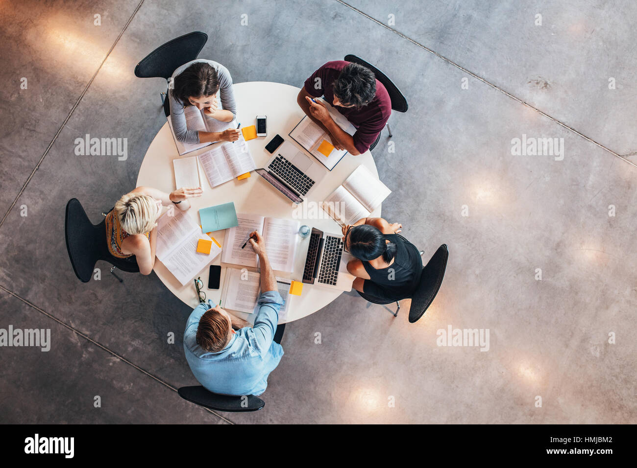Top view of university students sitting at a table studying and working ...