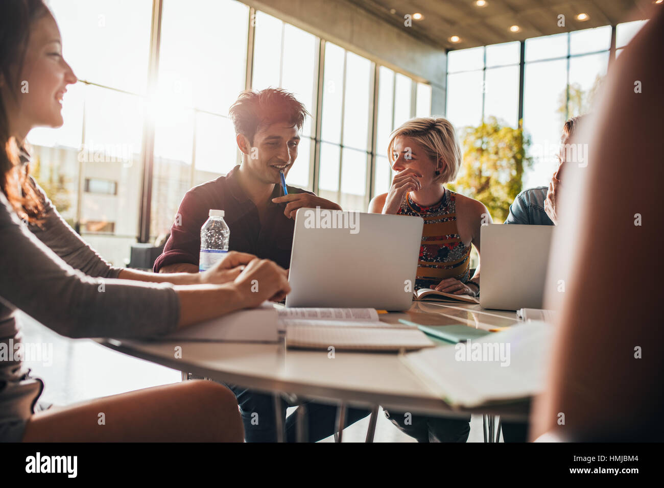 Happy friends using laptop while sitting in class. Group study in ...