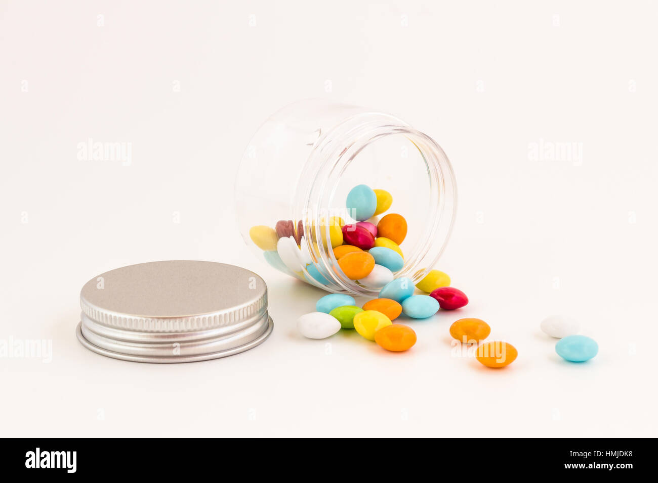 Colored smarties scattered out of an open glass jar, isolated on white ...