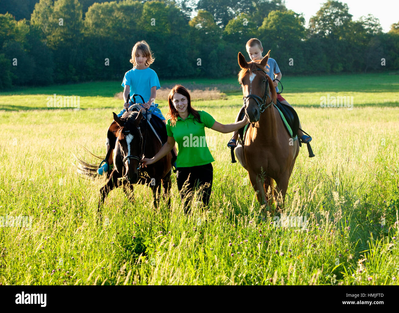 Horseback Riding Lessons - Woman Leading Two Horses with Boys Stock ...