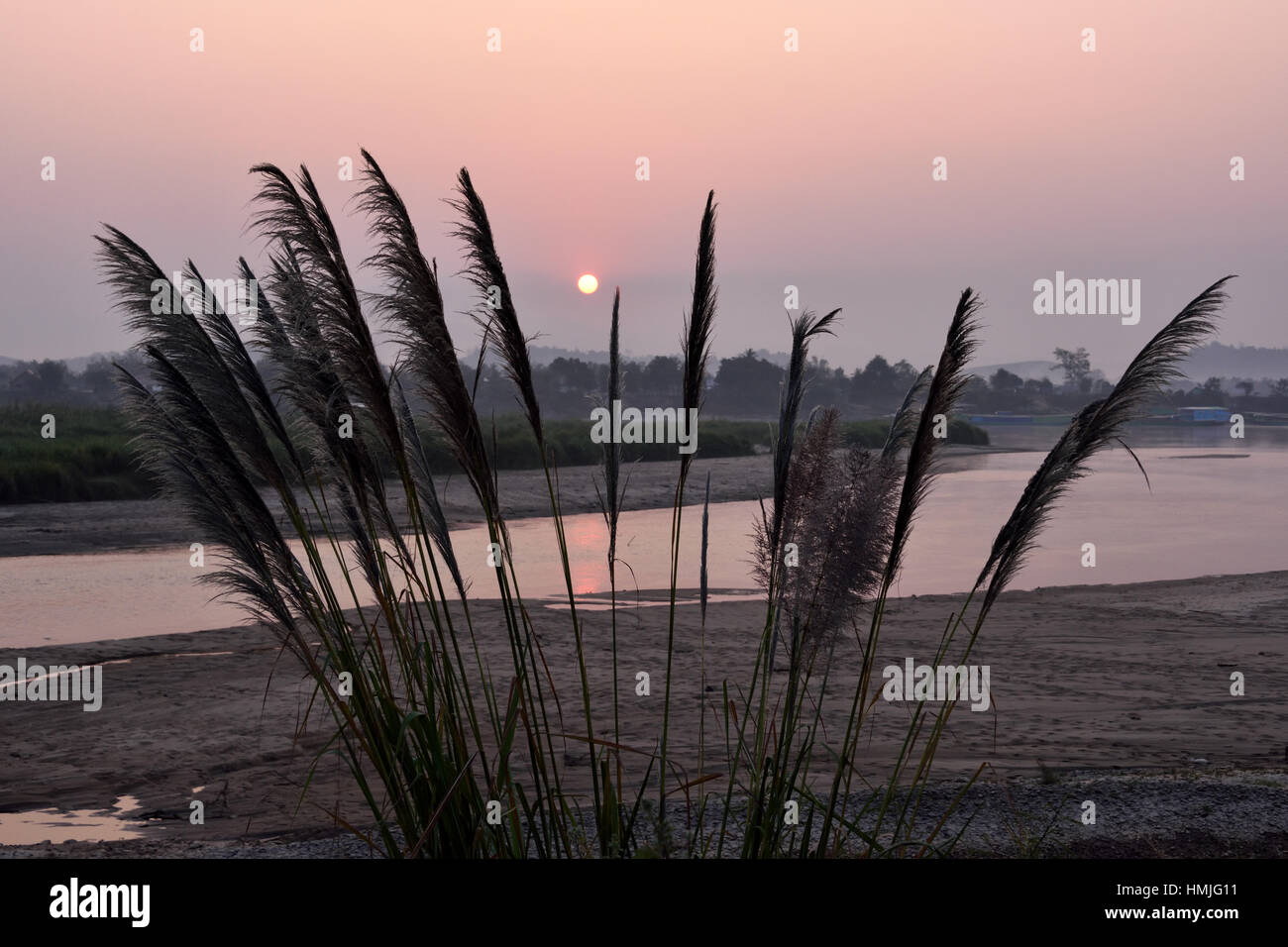 The sun rising over Loas on the Mekong River in Chiang Saen in Northern ...
