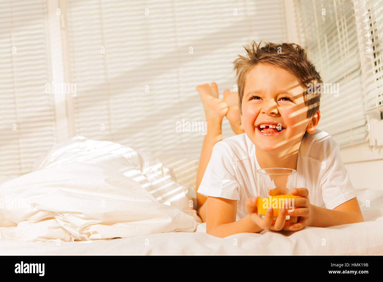Smiling boy laying in his bed with orange juice Stock Photo - Alamy