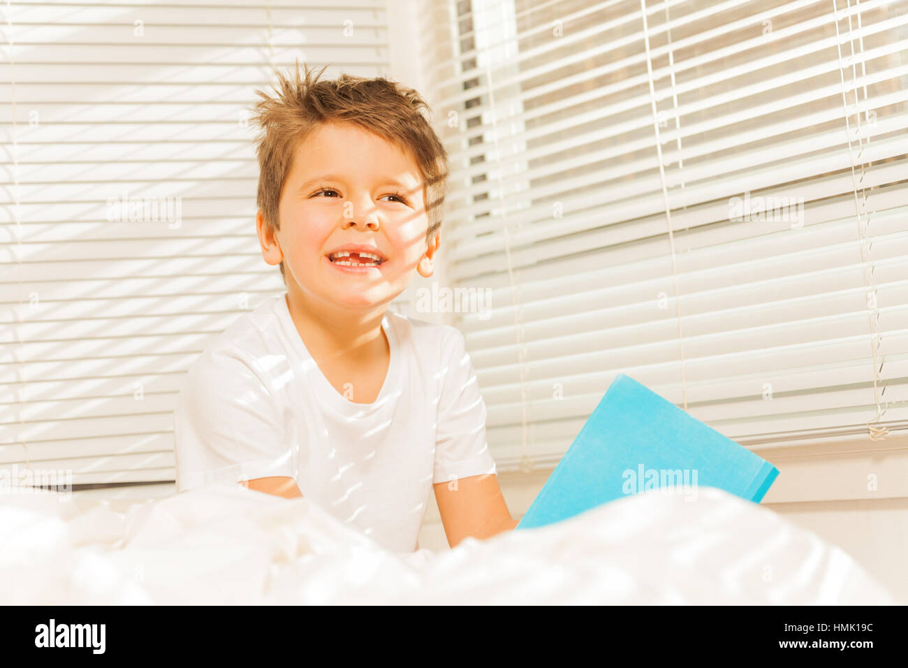 Thoughtful kid boy sitting in his bed with a book Stock Photo - Alamy