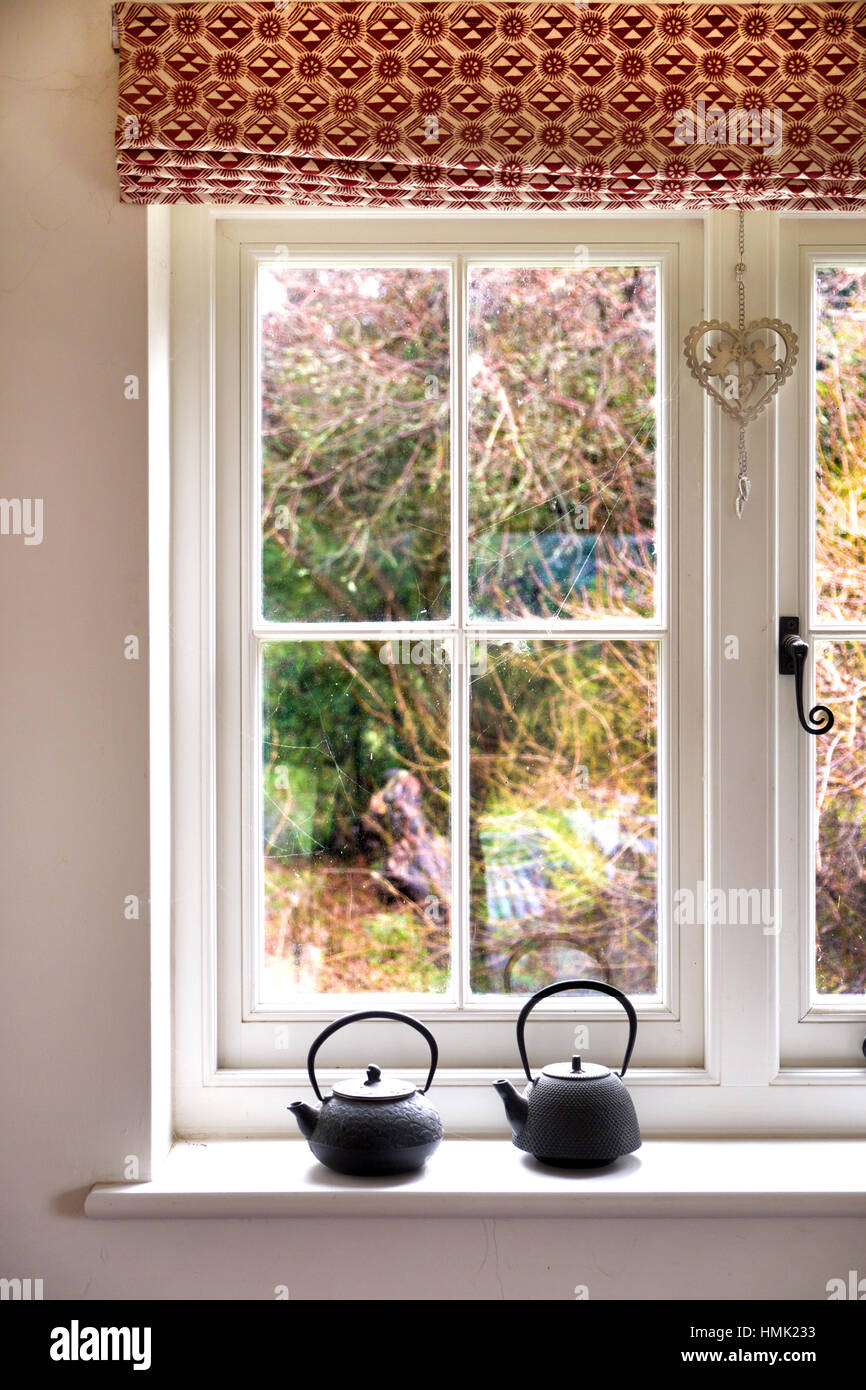 white window frame, with window sill with 2 small metal kettles on ...