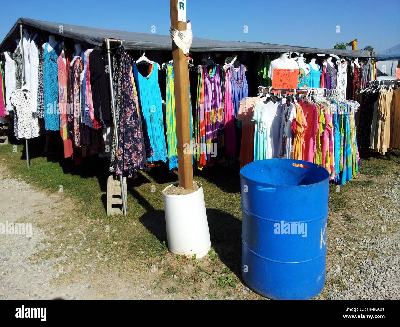 A blue barrel, signpost and hanging clothes in a vendor´s booth at an ...