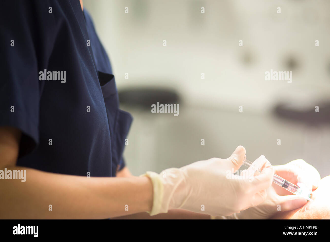 Anaesthetist injecting patient with anaesthetic in hospital ward ...