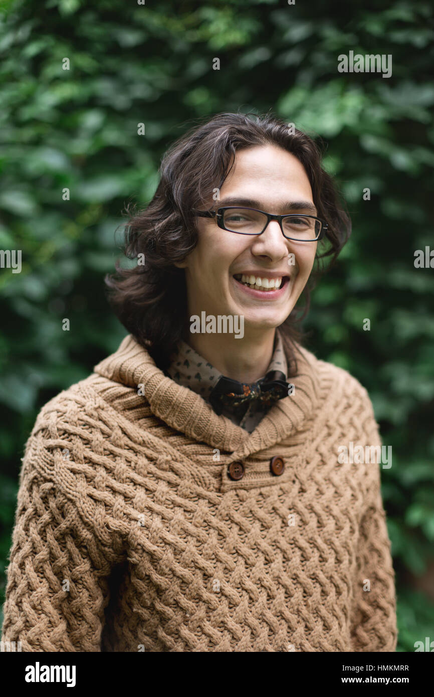 Young multiracial man smiling and standing against green background ...