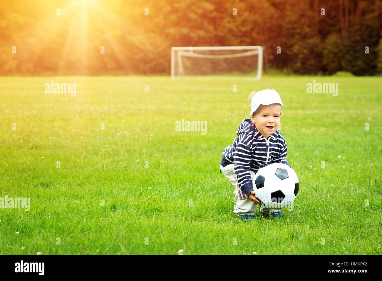 Little boy playing football on the field with gates Stock Photo - Alamy