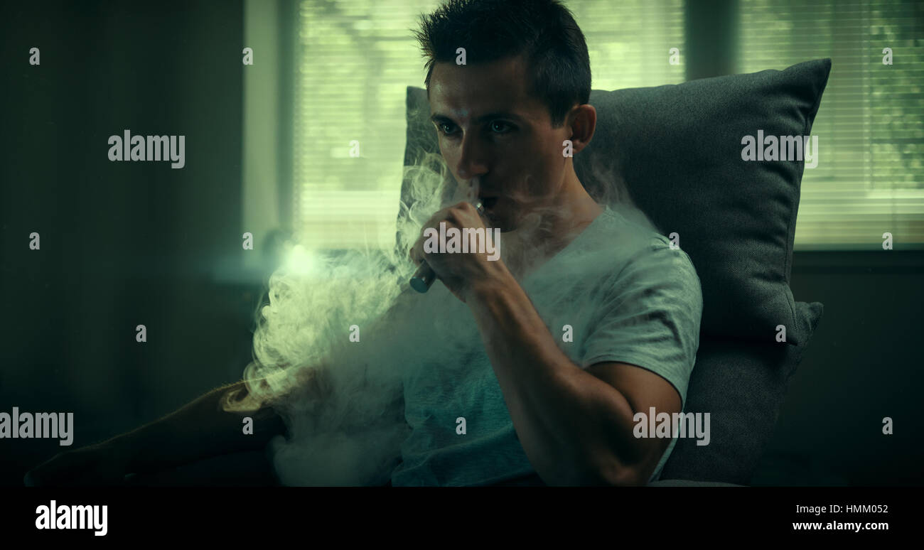 Stylish vaper. Young guy. Man using an advanced personal vaporizer or e ...