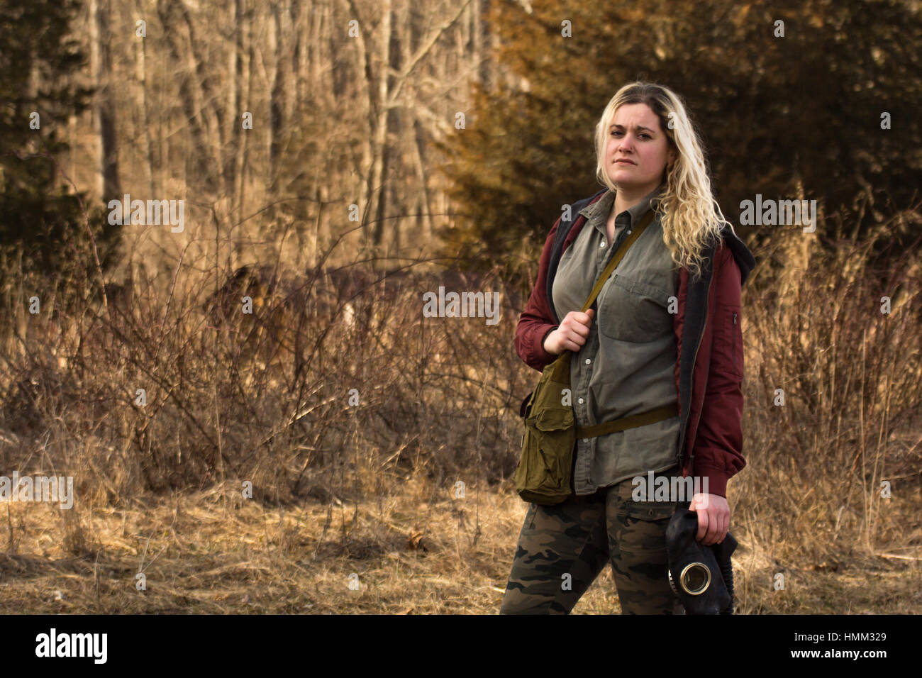 Worried pretty girl carrying authentic Russian gas mask through field ...