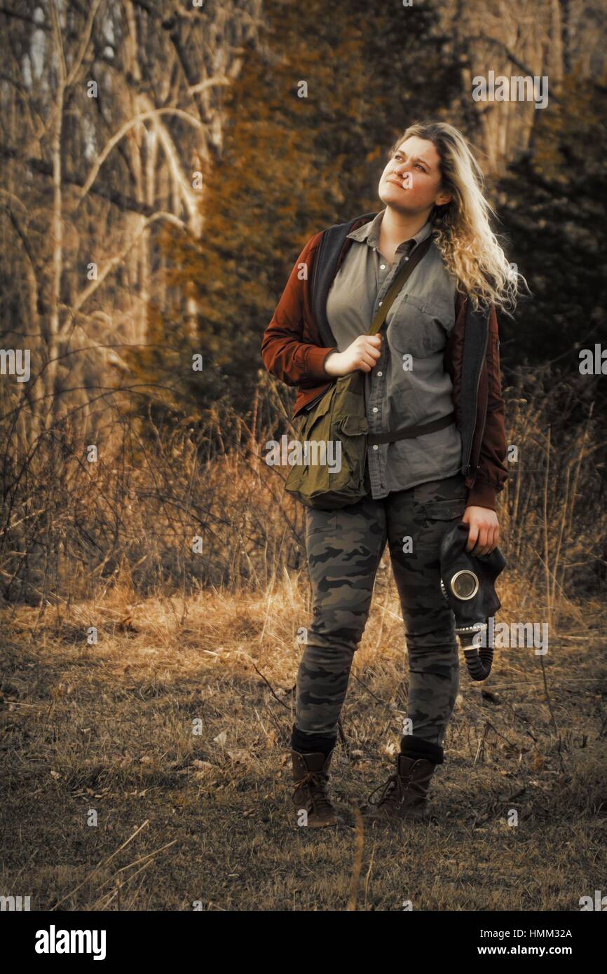 Worried pretty girl carrying authentic Russian gas mask through field ...