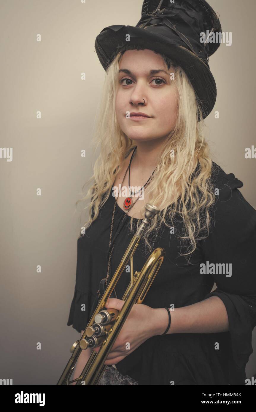 Stylish blonde gypsy girl wears top hat and plays trumpet Stock Photo ...