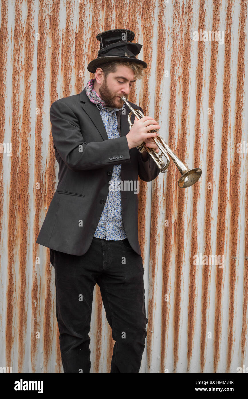 Stylish bearded gypsy plays trumpet by rusty fence Stock Photo - Alamy