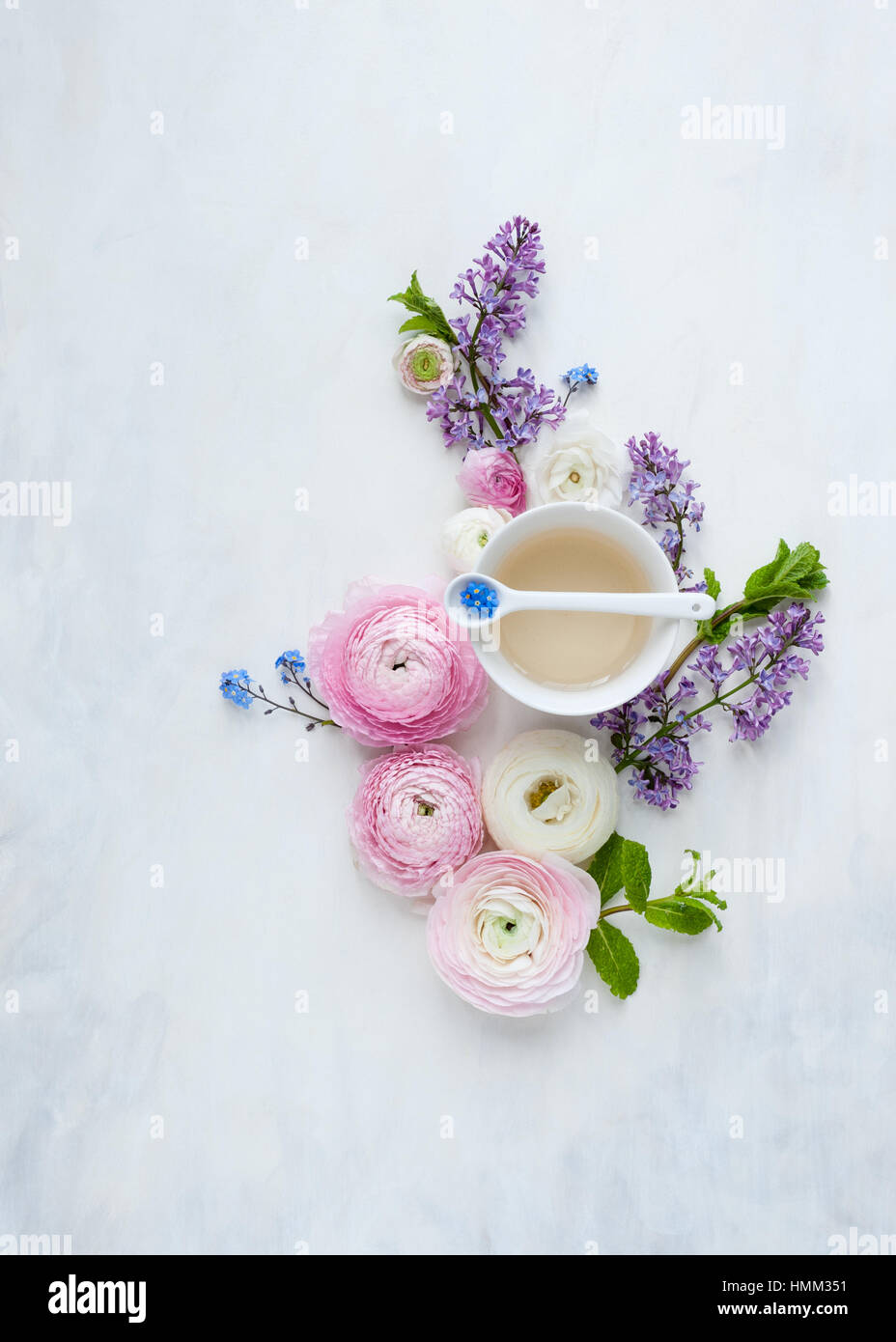 Flat lay of spring flowers and teacup on a painted white and grey ...