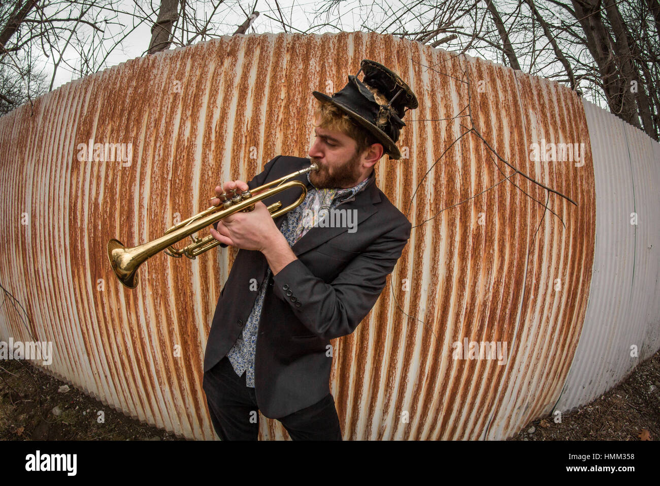 Stylish bearded gypsy plays trumpet by rusty fence Stock Photo - Alamy