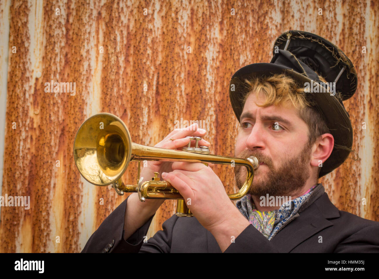 Stylish bearded gypsy plays trumpet by rusty fence Stock Photo - Alamy
