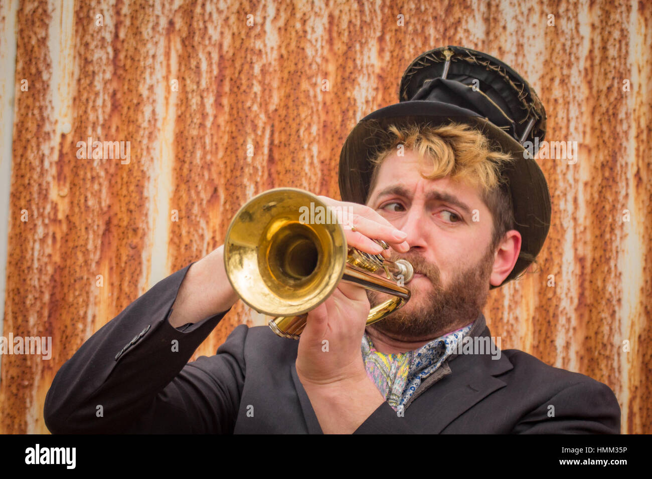 Stylish bearded gypsy plays trumpet by rusty fence Stock Photo - Alamy