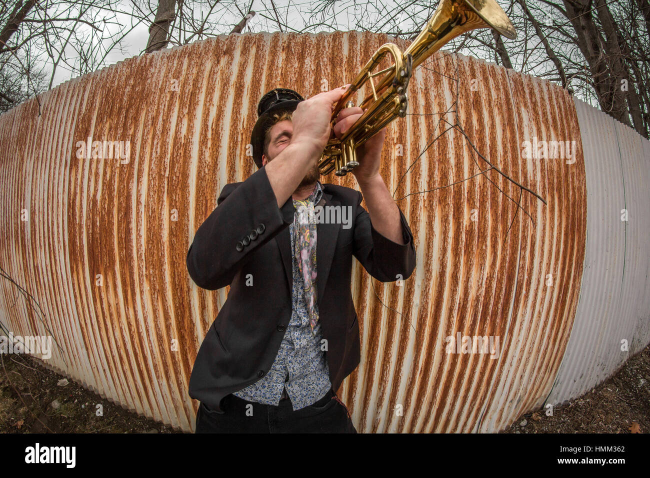 Stylish bearded gypsy plays trumpet by rusty fence Stock Photo - Alamy