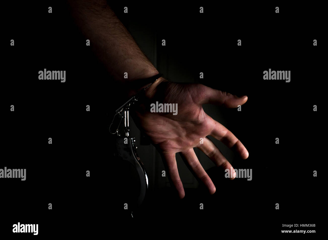 Unlocked handcuffs on male hand on black background Stock Photo - Alamy