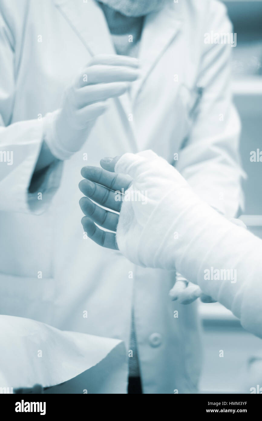 Doctor applying a plaster cast and bandages to patient forearm and ...