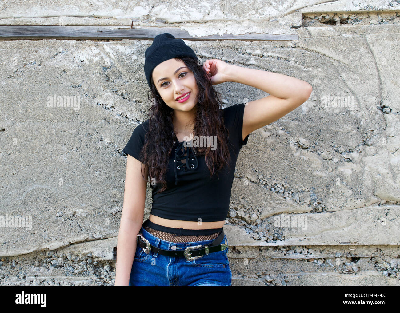 Portrait of beautiful, adult female model posing against cement wall ...