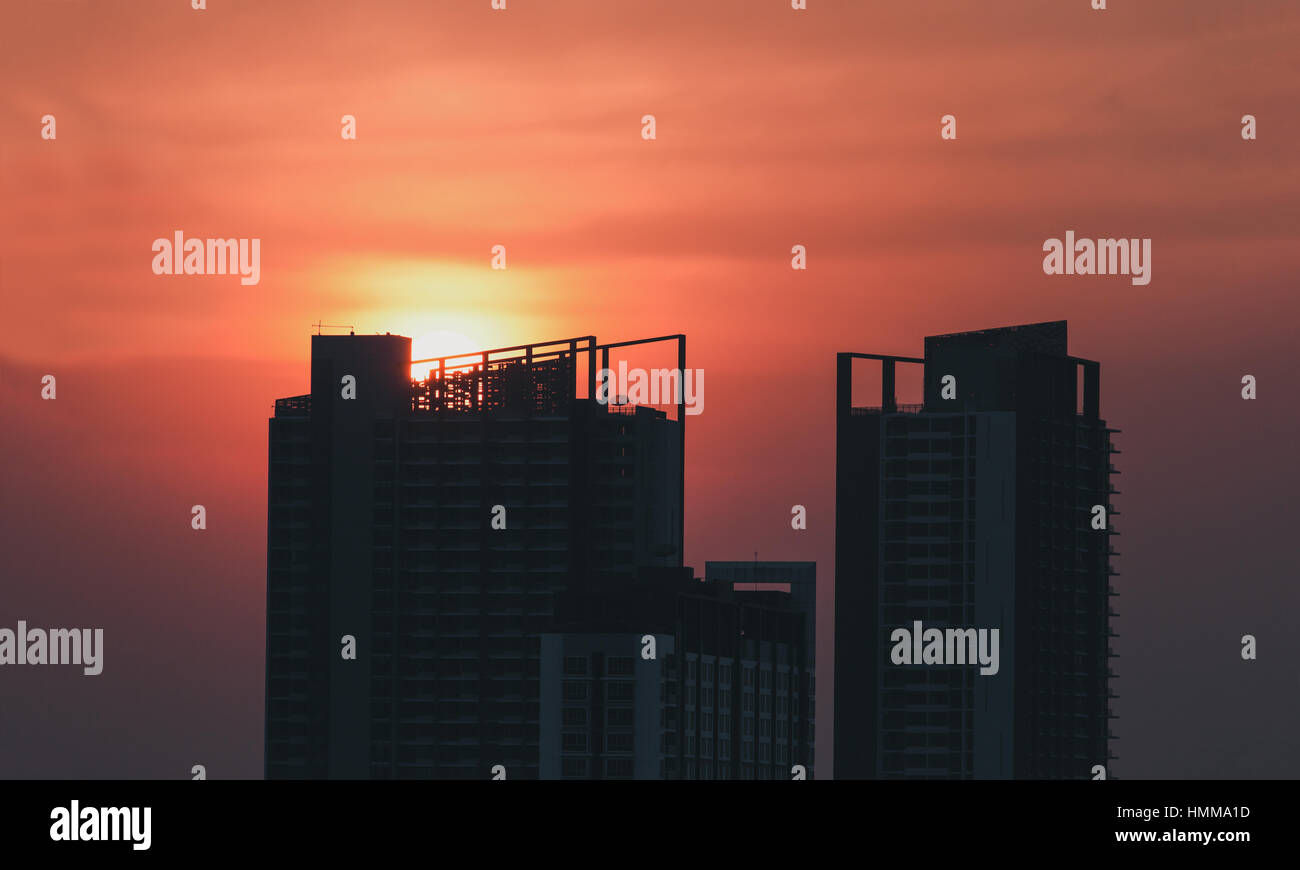 Silhouette top of building with sunset on orange sky Stock Photo - Alamy