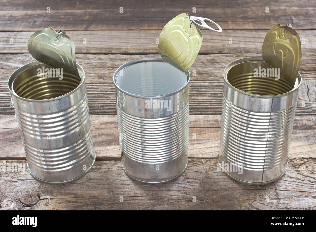 Three open empty tin can on wooden background Stock Photo - Alamy