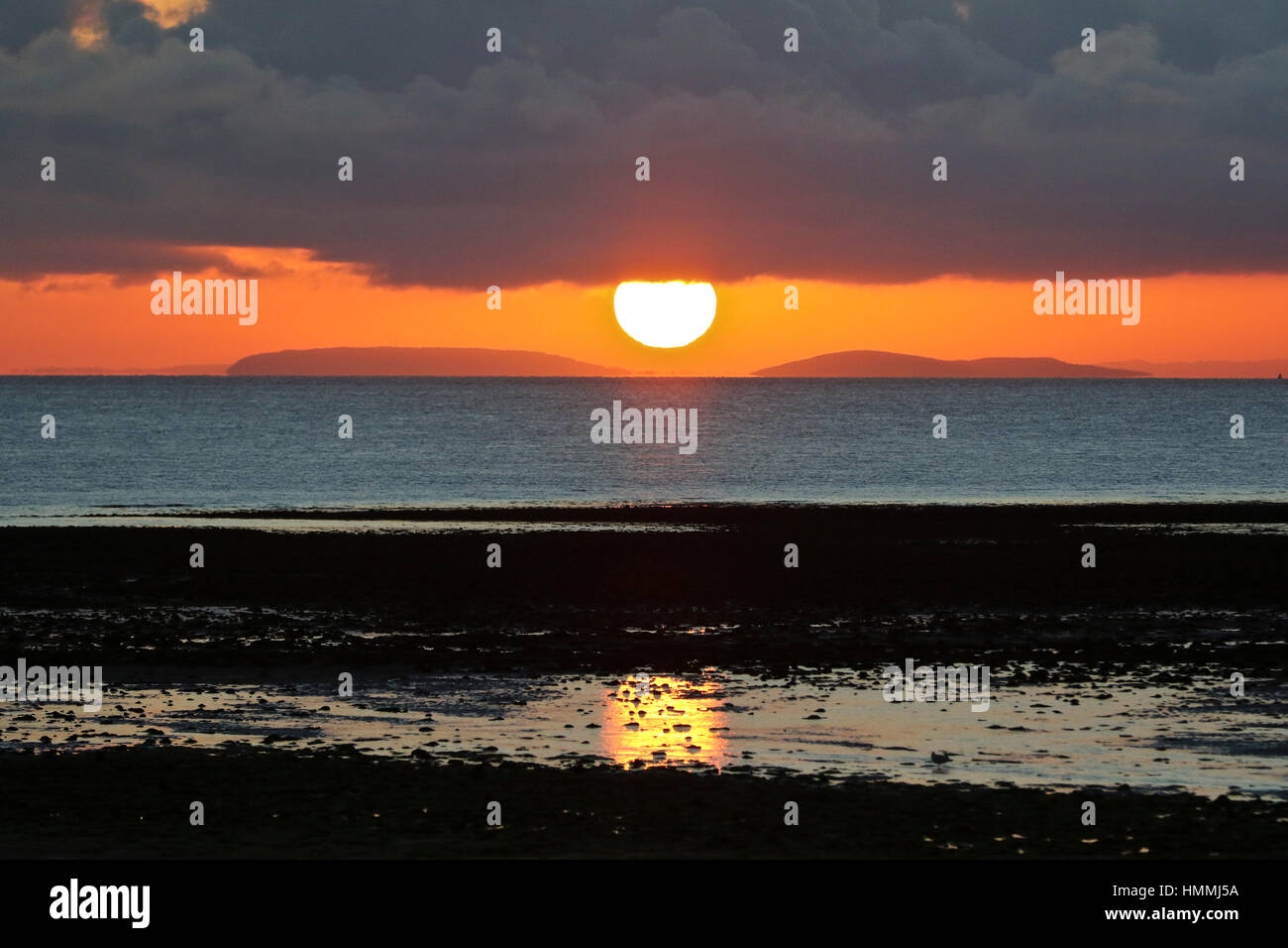 Sun rising over Dunster Beach Stock Photo - Alamy