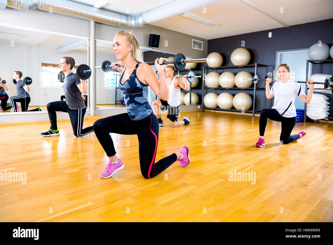 Smiling team do split squats with weights at fitness gym Stock Photo ...