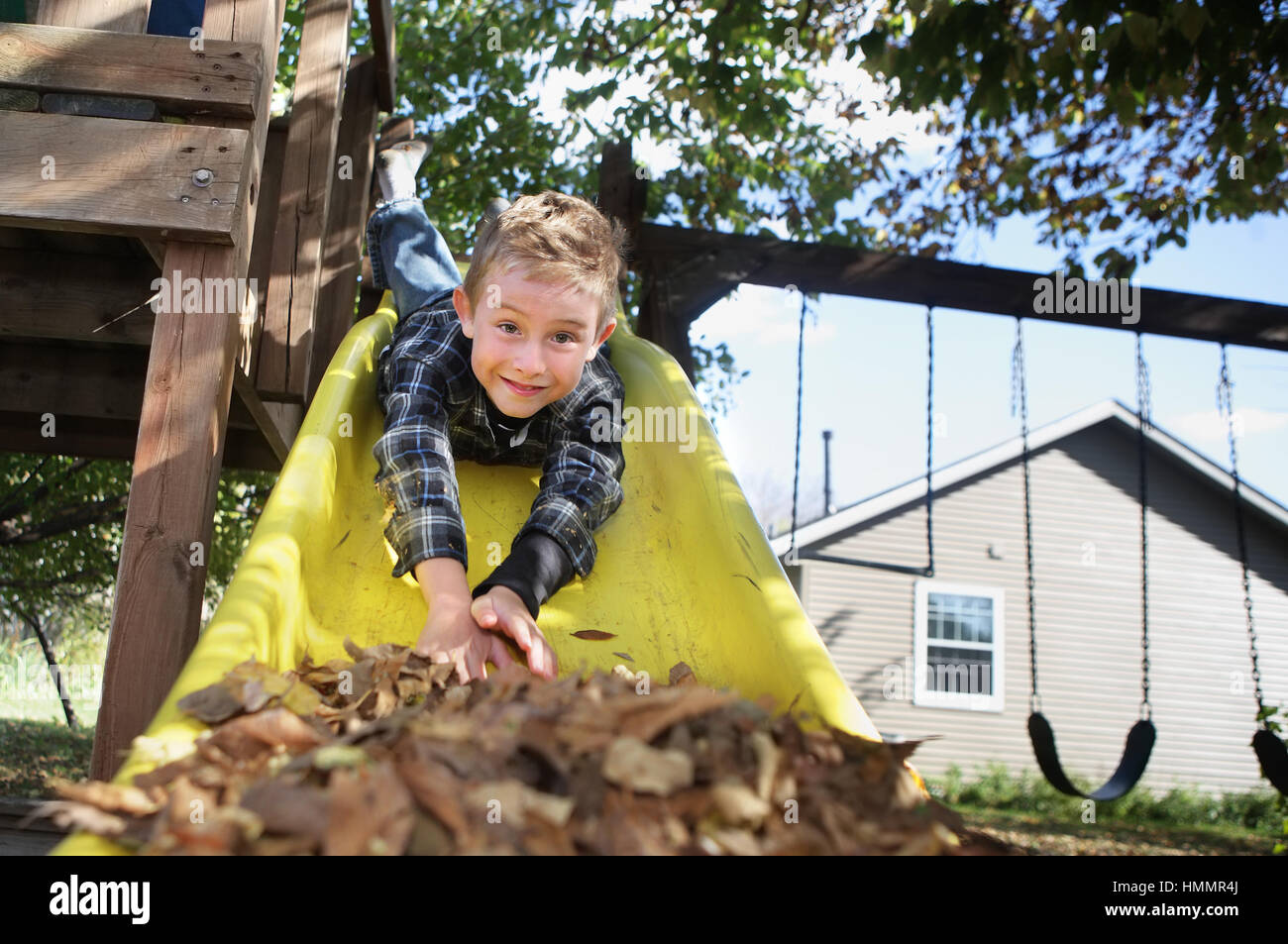 A young boy sliding down a slide into a pile of fall leaves Stock Photo ...