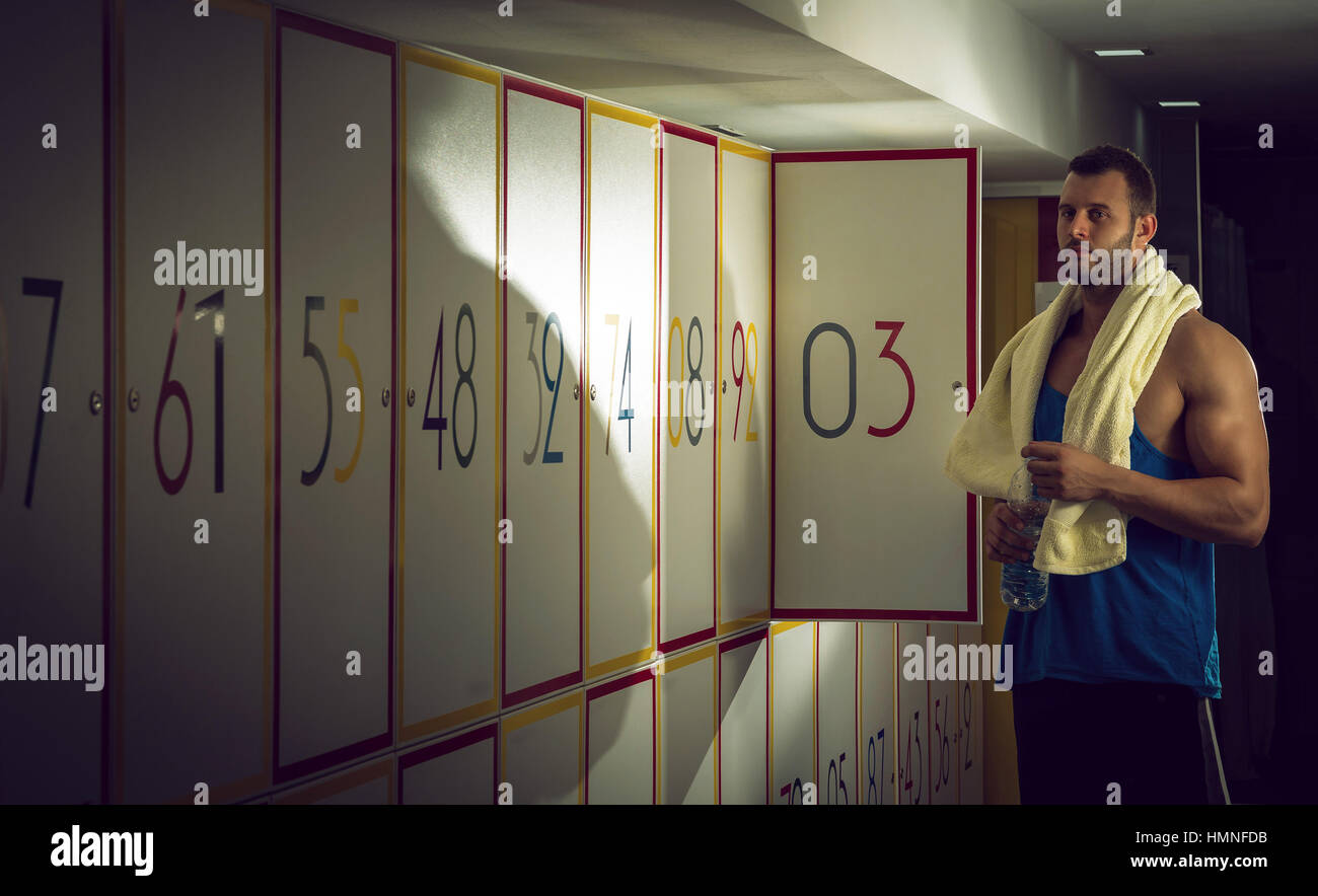 Young adult fit man standing in locker room and opening locker door Stock Photo - Alamy