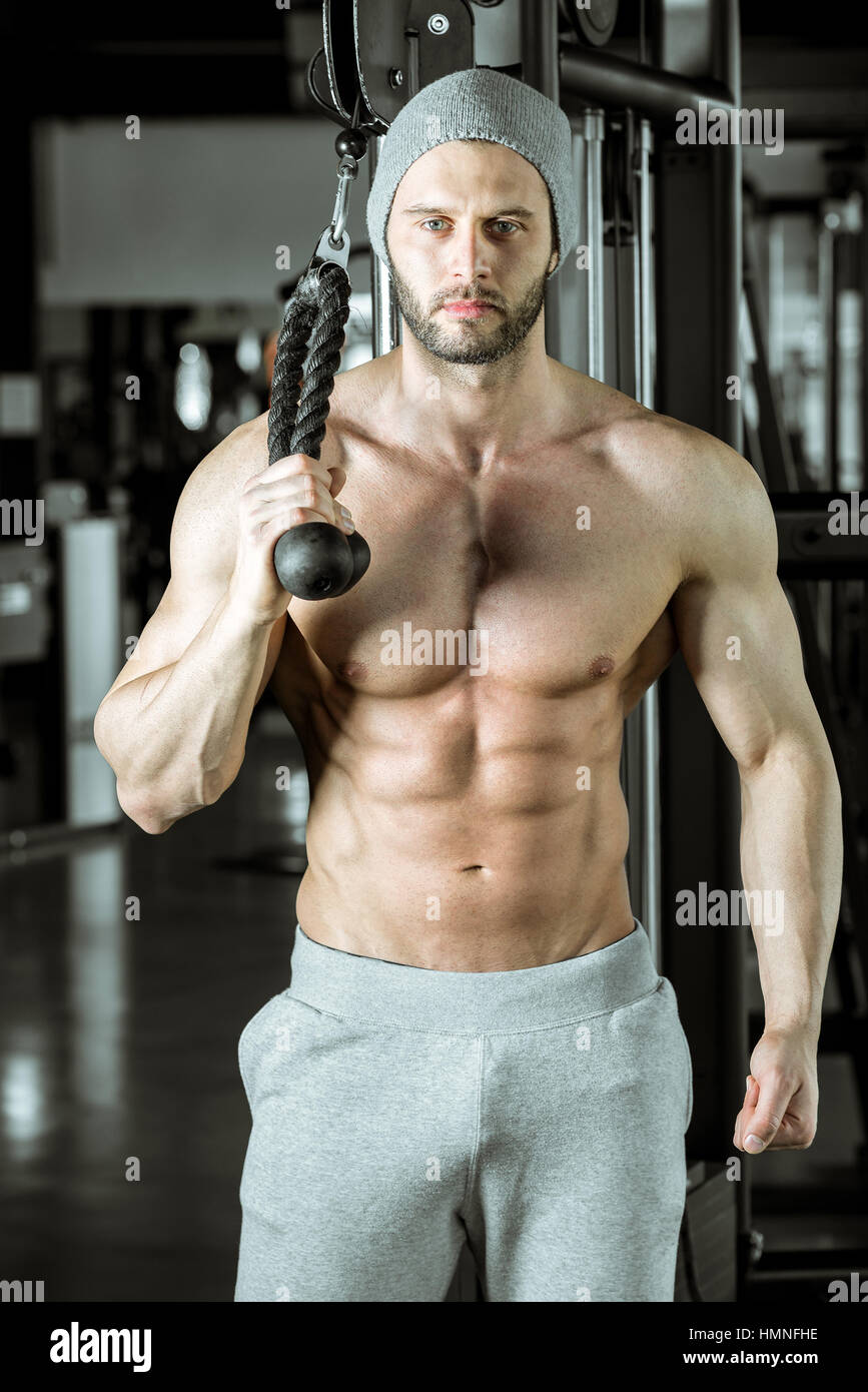 Young adult bodybuilder doing triceps overhead extension rope exercise ...