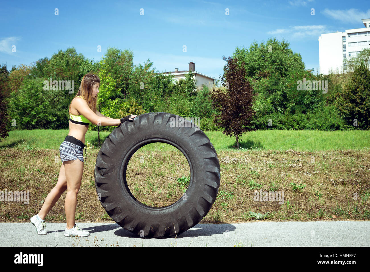 Young adult woman flipping and rolling tire during crossfit exercise ...