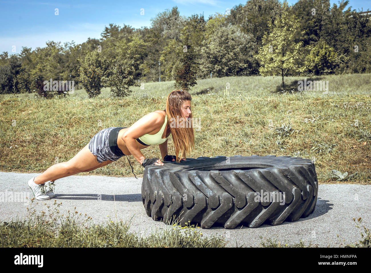 Strong female doing outdoor exercise with tyre. Toned image Stock Photo ...