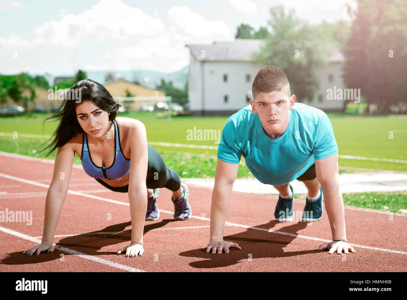 Young adult couple doing together push ups exercise outdoor on running ...