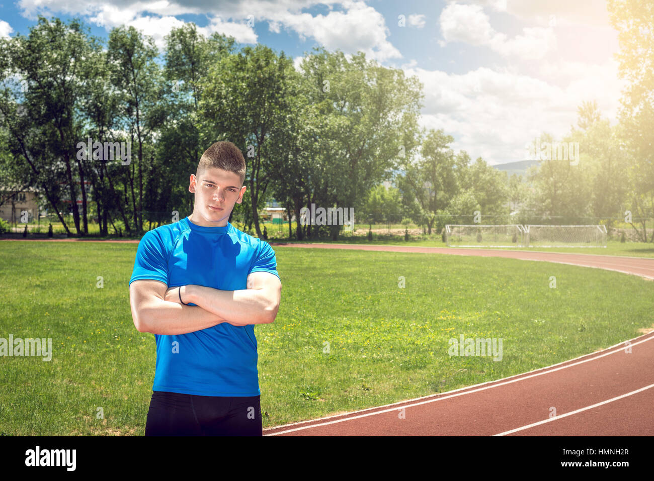 Handsome athletic man posing on track field outdoor while relaxing ...