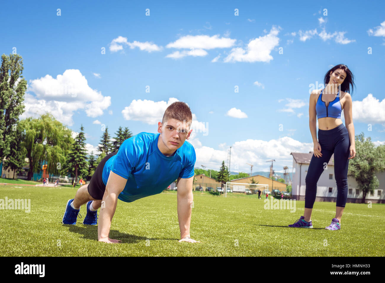 Young athlete doing push ups outdoor on grass football field together ...