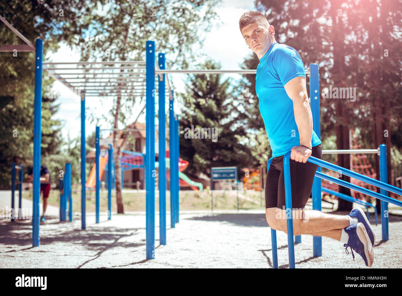 Young fit man doing dips exercise outdoor in open air gym. Toned image ...