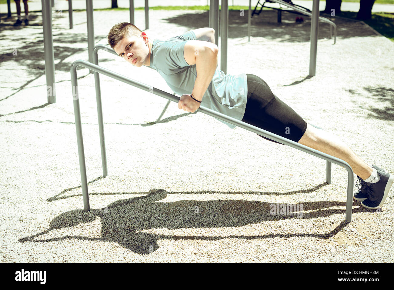 Young adult fit bodybuilder doing push-ups exercise in outdoor park gym ...