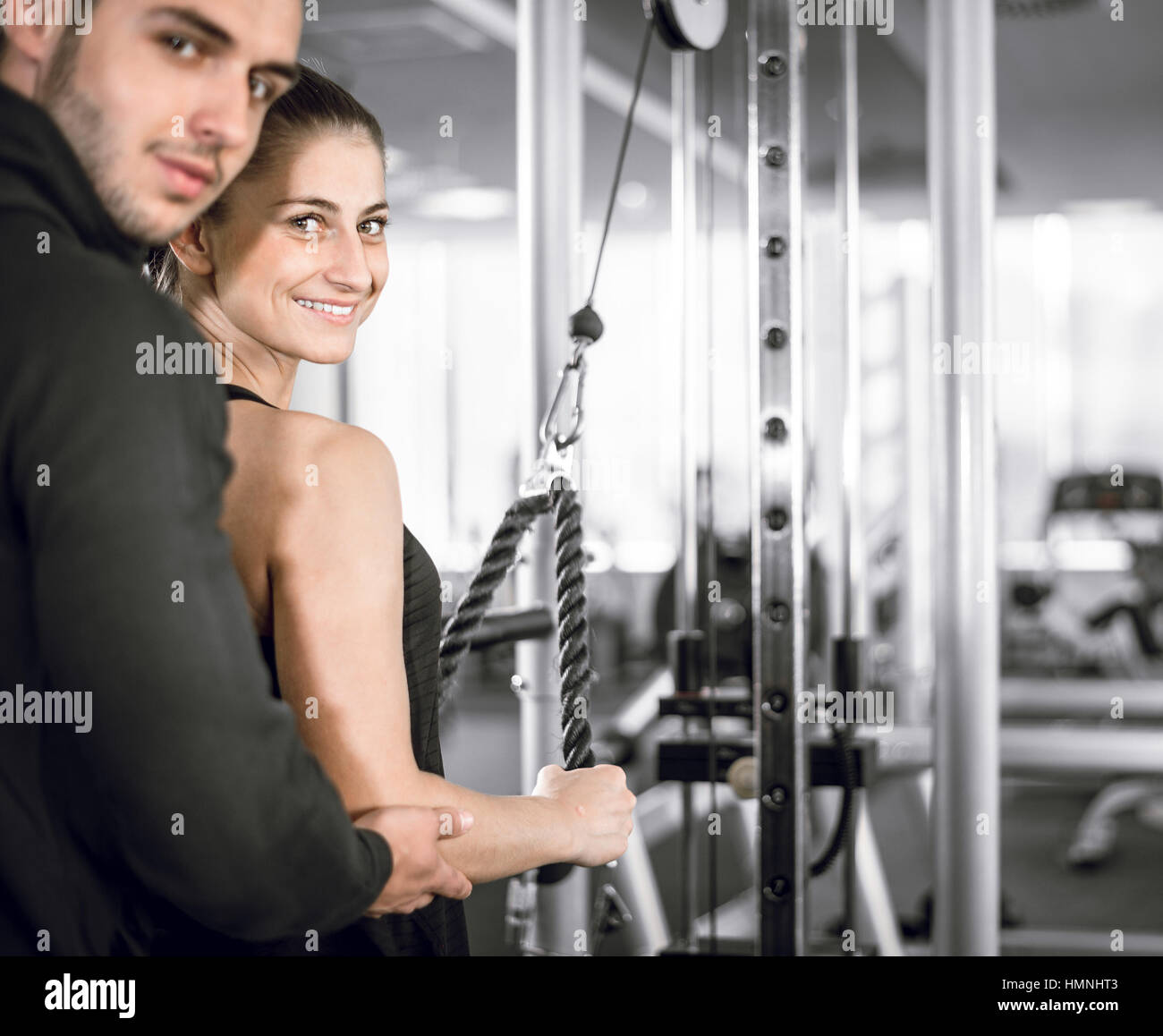 Young adult personal fitness trainer supporting his client while doing ...