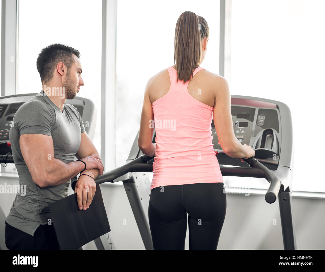 Personal fitness trainer watching his private client while walking on ...