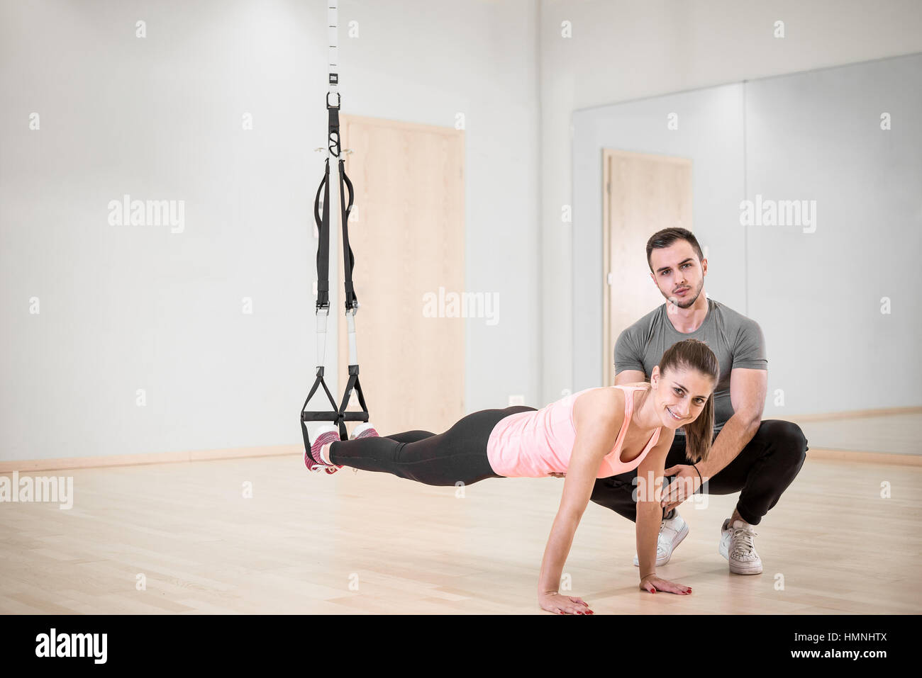 Young adult girl doing suspension rope exercise together with her ...