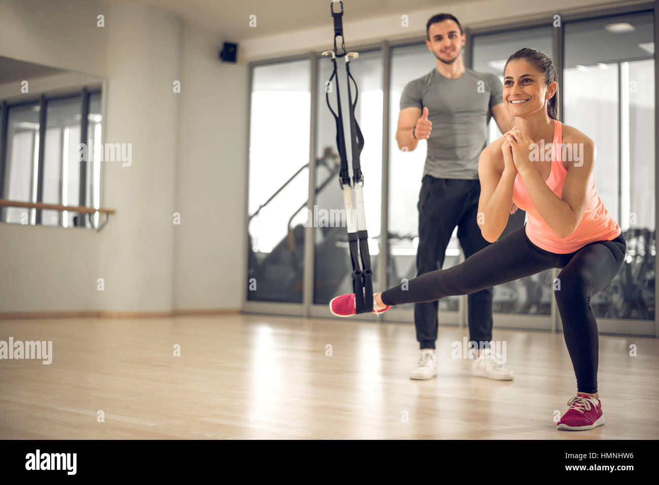 Young adult girl doing suspension rope exercise together with her ...