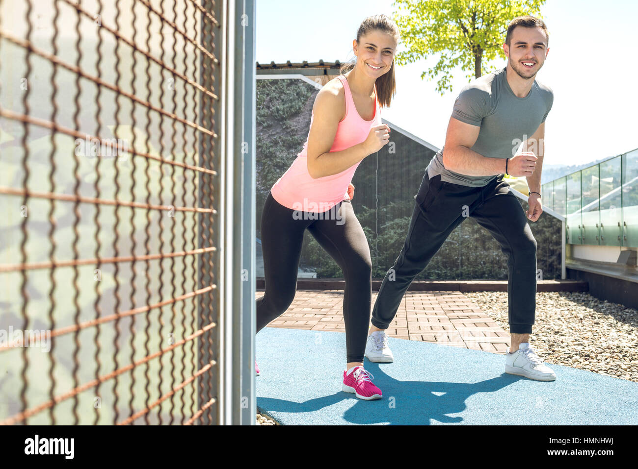 Fitness couple running together on modern track on rooftop of building ...