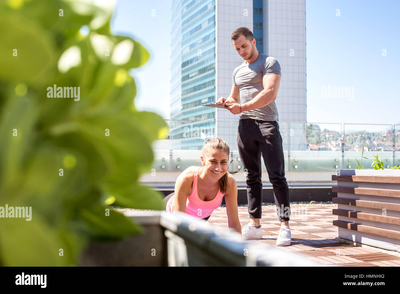 Personal trainer support and motivate his client while doing push ups ...