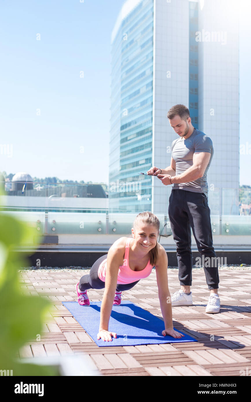 Personal trainer support and motivate his client while doing push ups ...