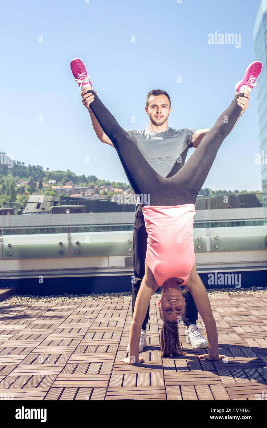 Female fitness woman doing handstand while her personal coach supports ...