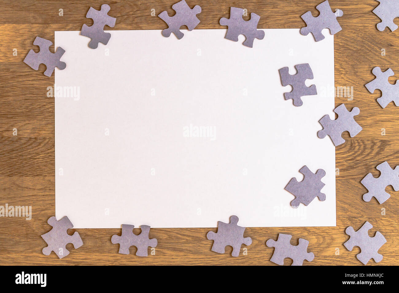 Blank sheet of paper surrounded by puzzle pieces on wooden background ...